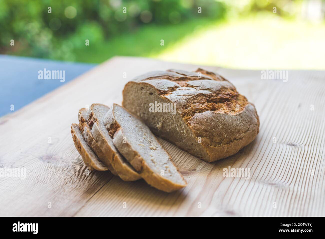 Fresh dark bread in slices, lying on a wooden cutting board. Defocused ...