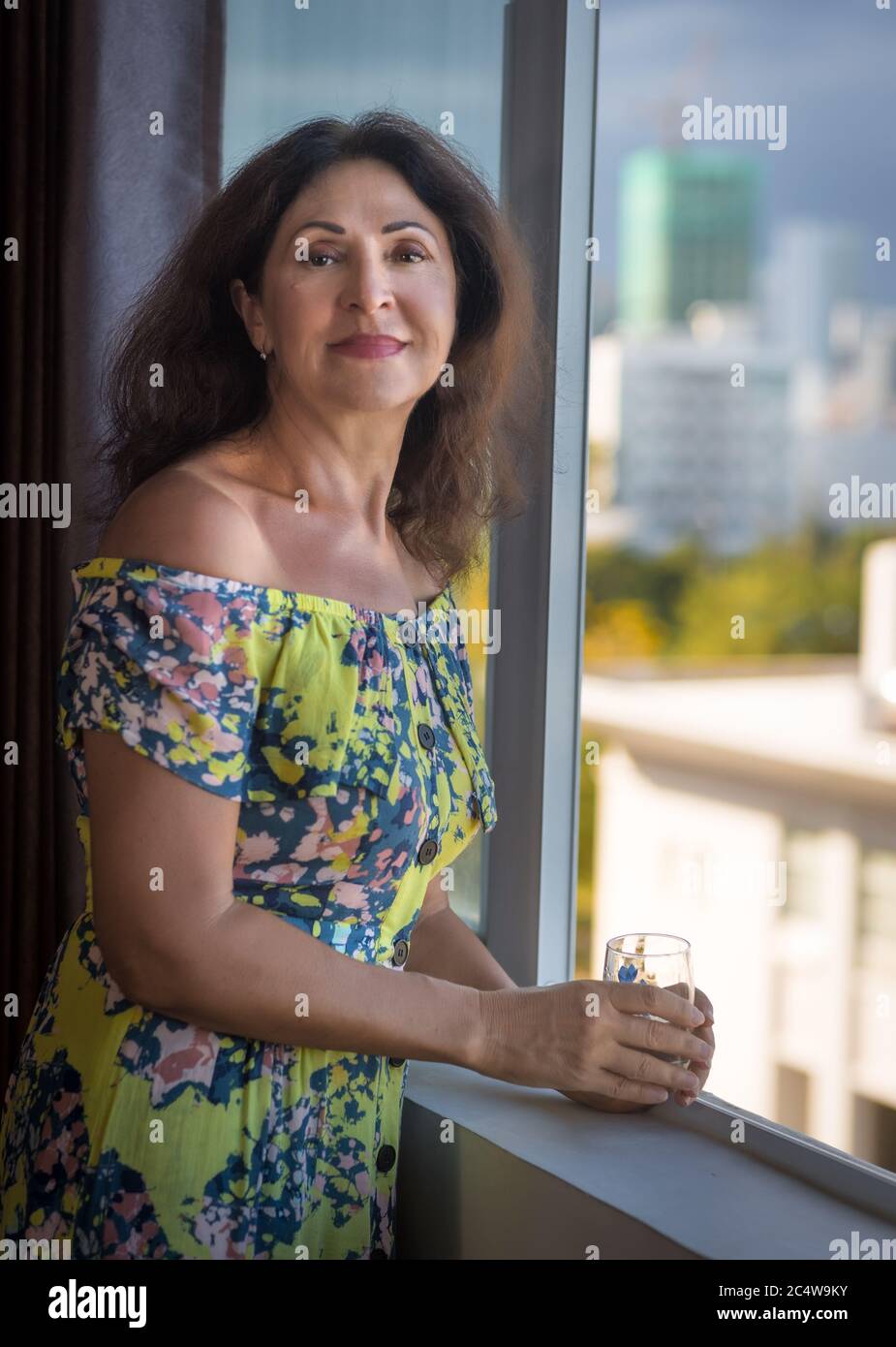 Indoor portrait of a beautiful smiling senior woman next to window ...