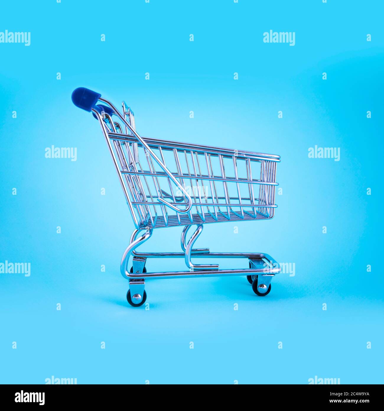 empty shopping cart over blue background, mini metal cart isolated on ...