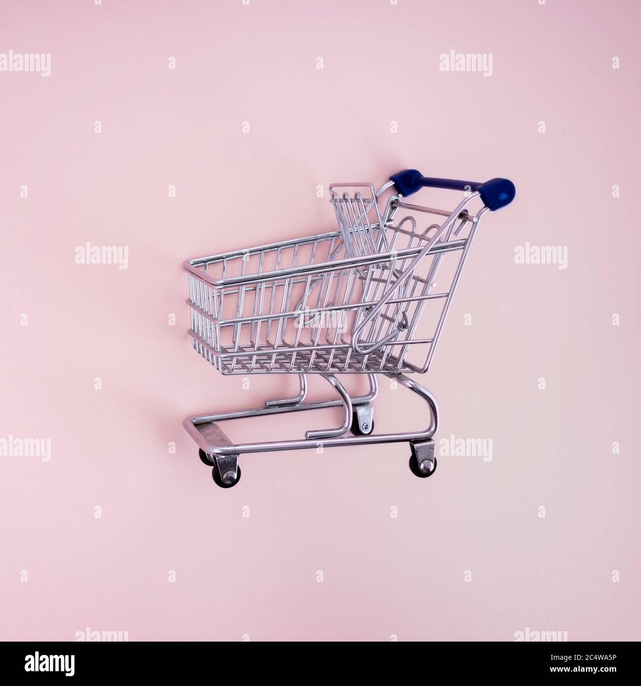 empty shopping cart over pink background, mini metal cart isolated on ...