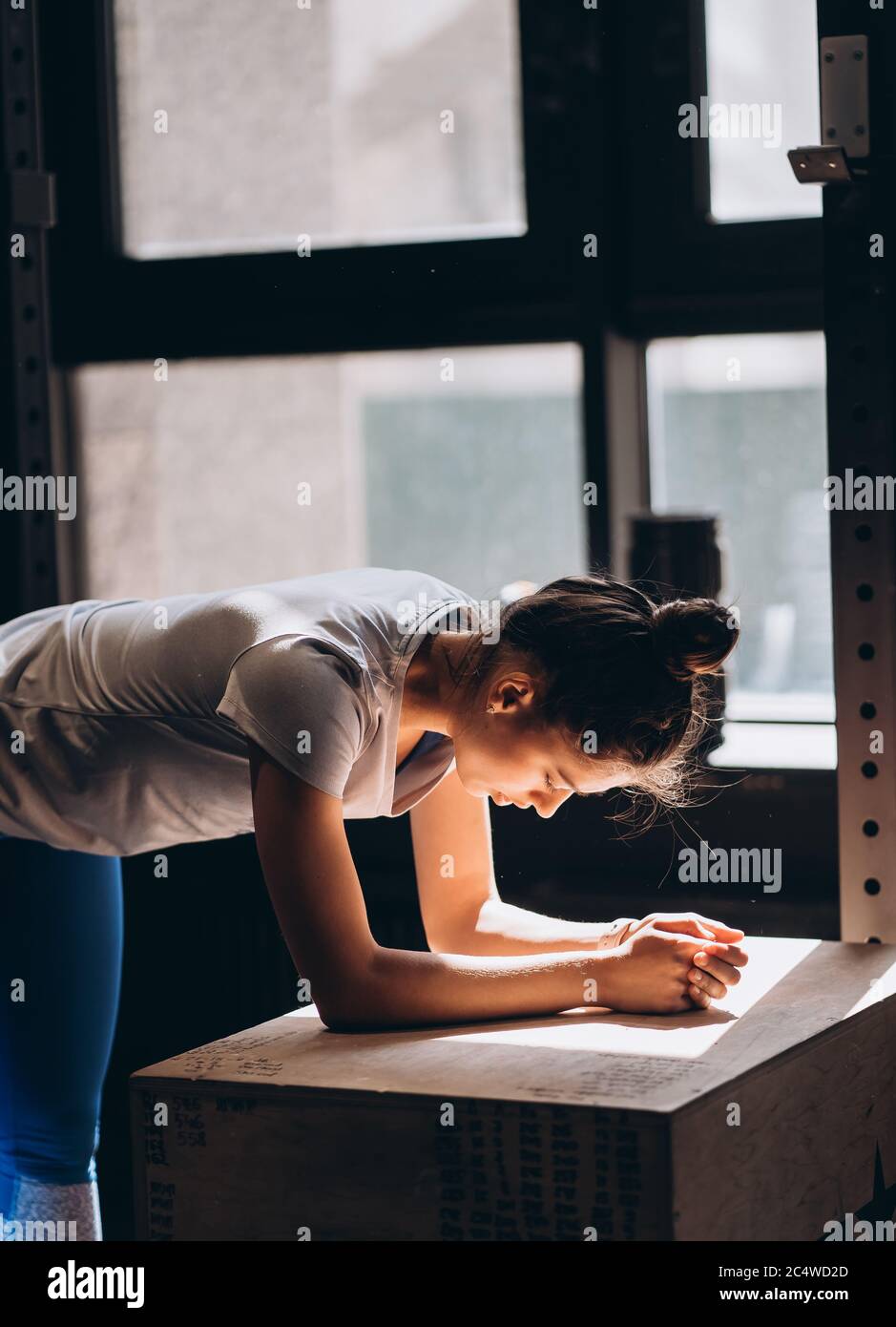 Beautiful woman leaned over the table against window Stock Photo - Alamy