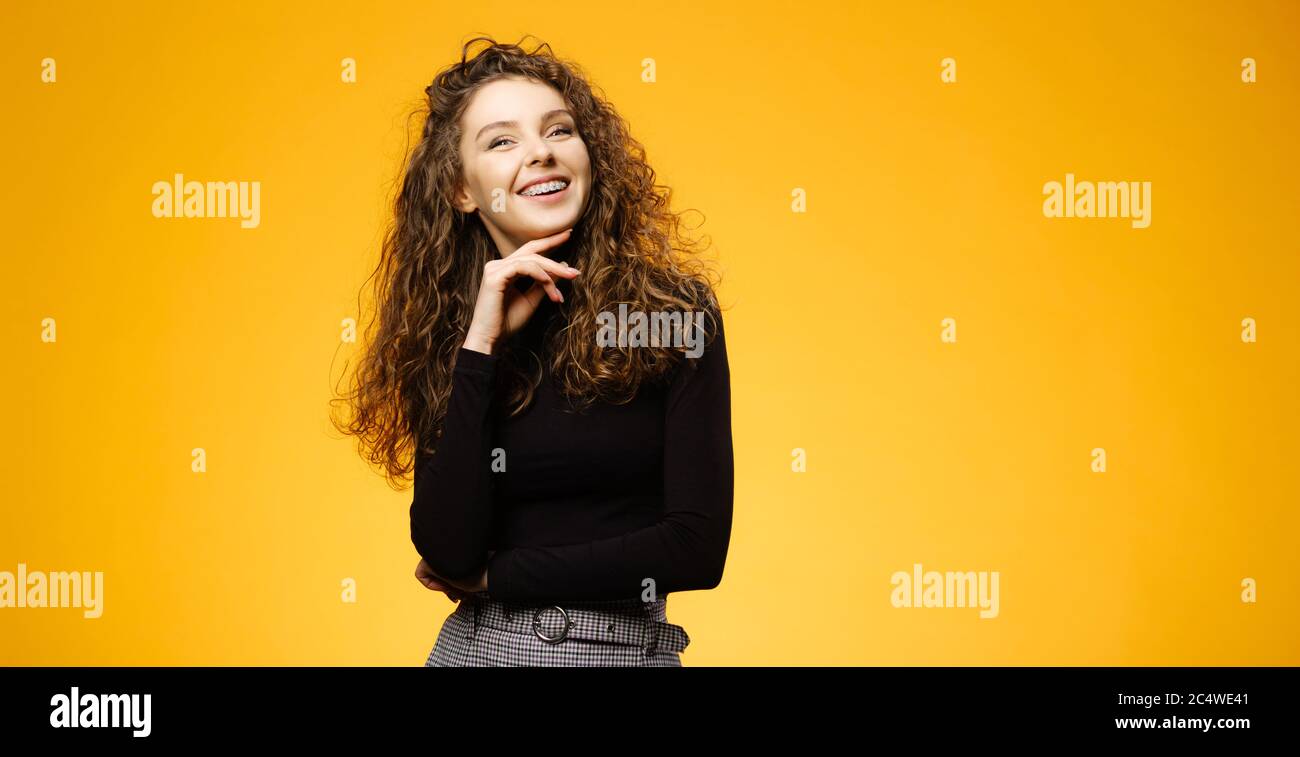 Pretty girl with curly hair isolated on yellow background. Model ...