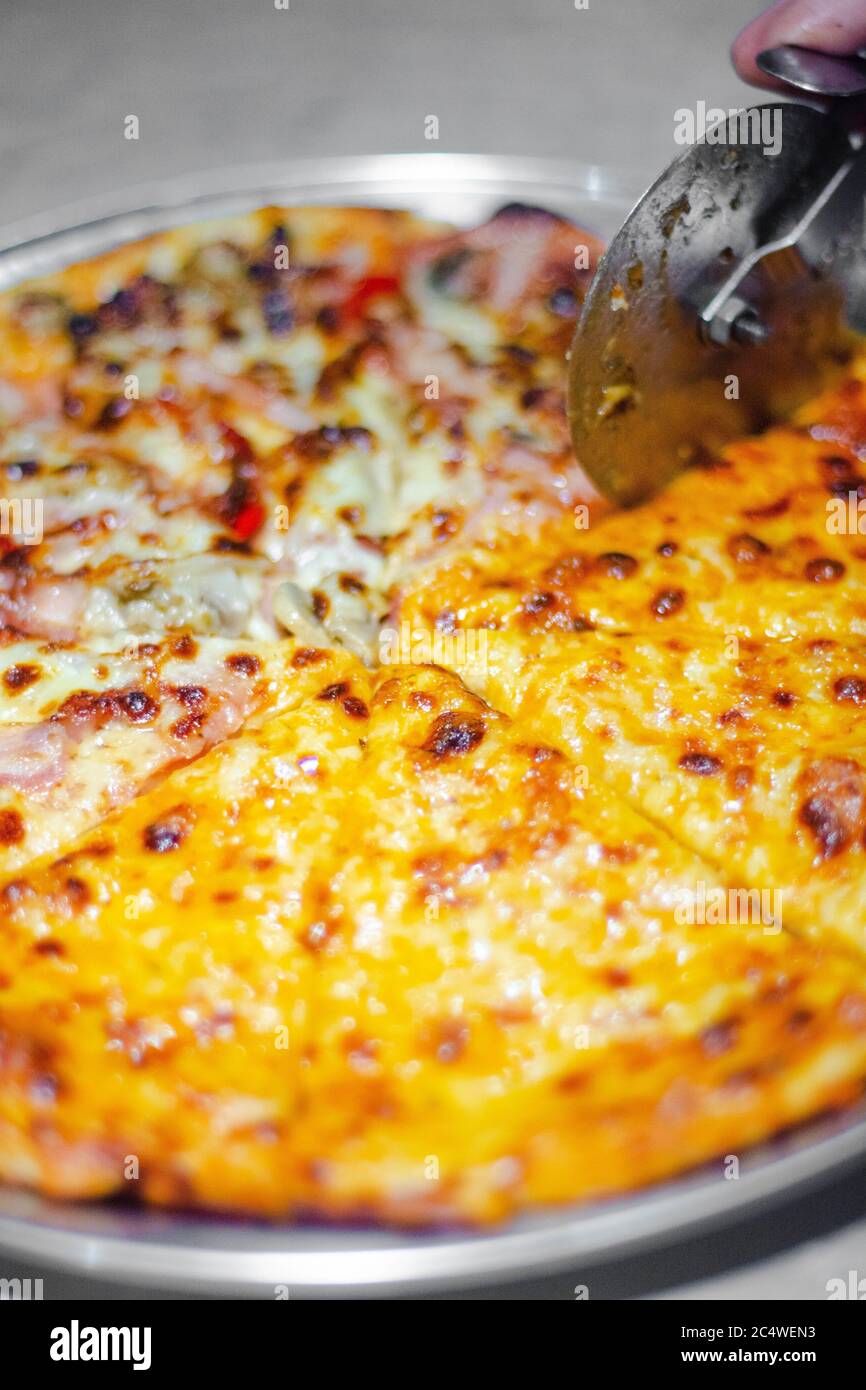 Process of cutting pizza with a special knife Stock Photo - Alamy