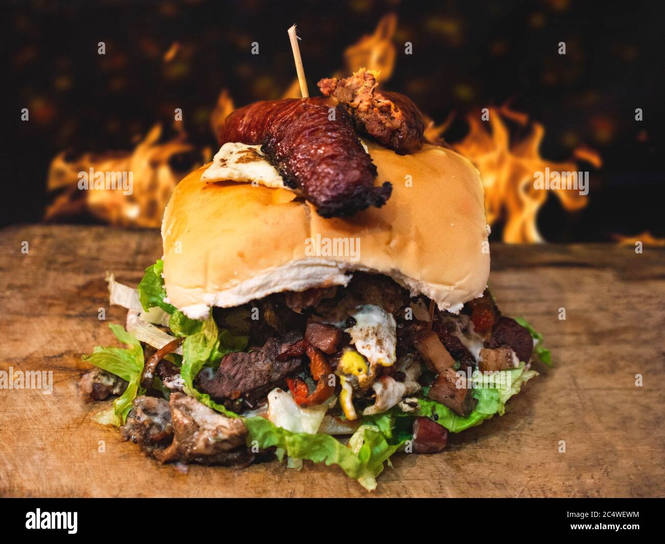 Delicious beef burger on a wooden table with a fire in a background ...