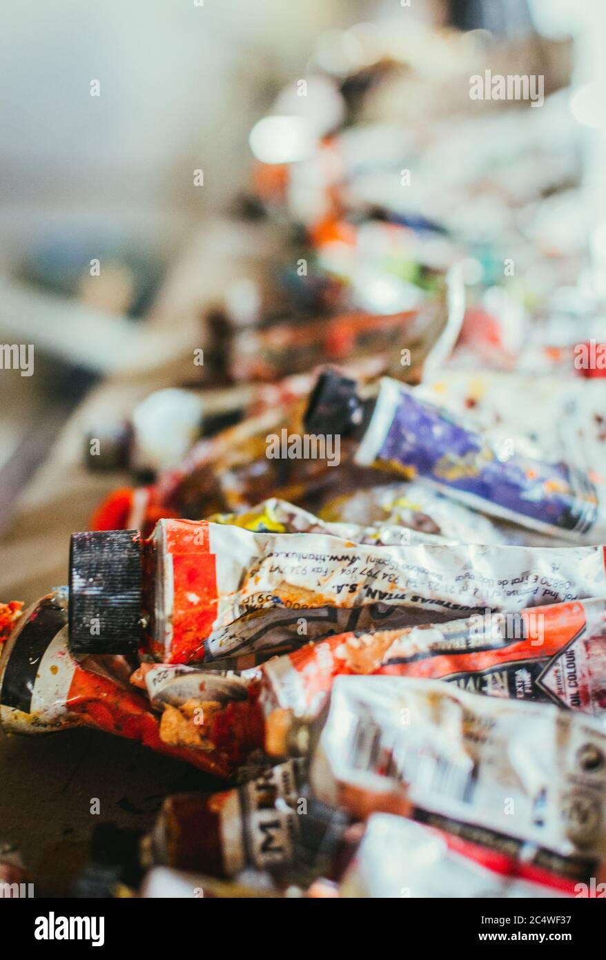 Vertical closeup shot of a lot of colorful paint tubes on the table ...