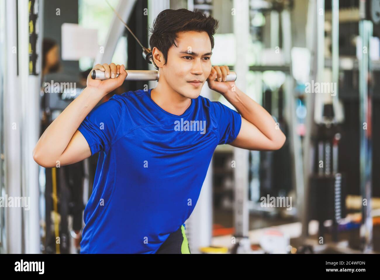 Young Asian man wearing sportswear doing excecise with the bar in gym ...