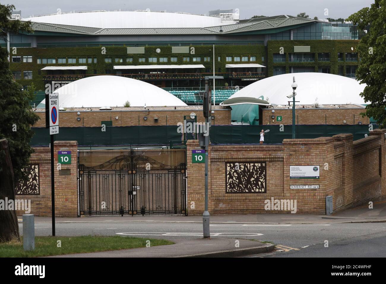 A tennis player strikes a ball on an outdoor hard court behind gate ten ...