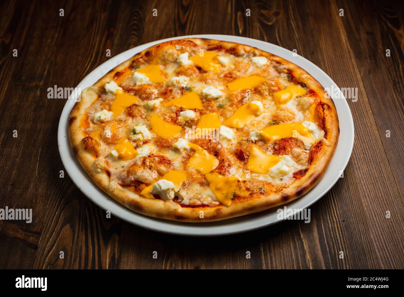 Four kinds of cheese pizza, wooden background, low key Stock Photo - Alamy