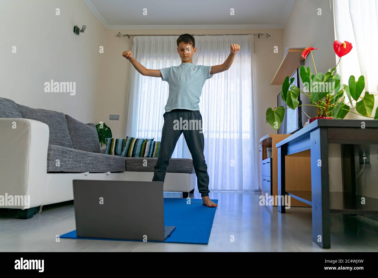 Boy with laptop computer doing sport exercises, practicing yoga at home ...
