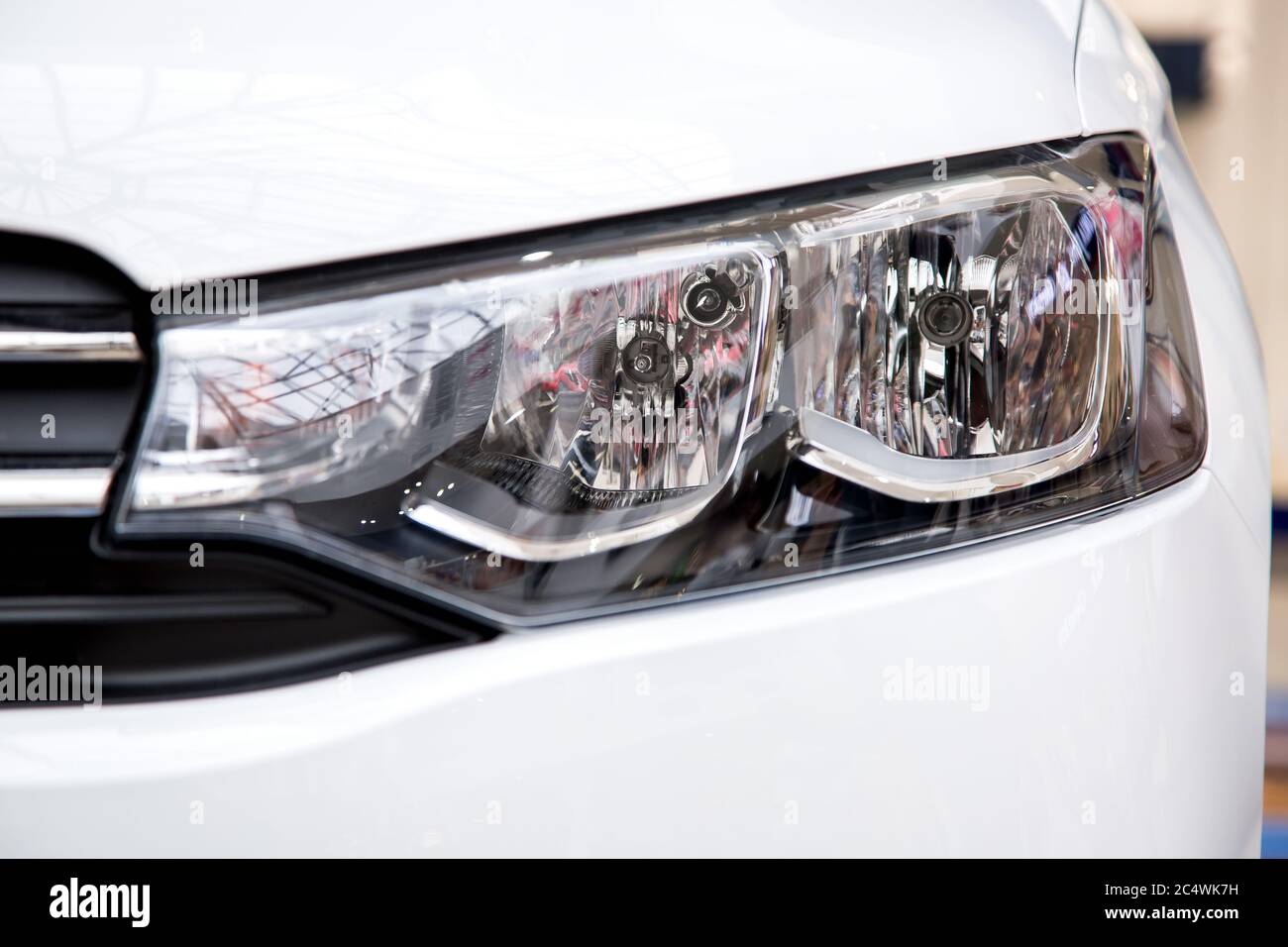 Front halogen headlight of a white car, a new car's headlight close-up ...