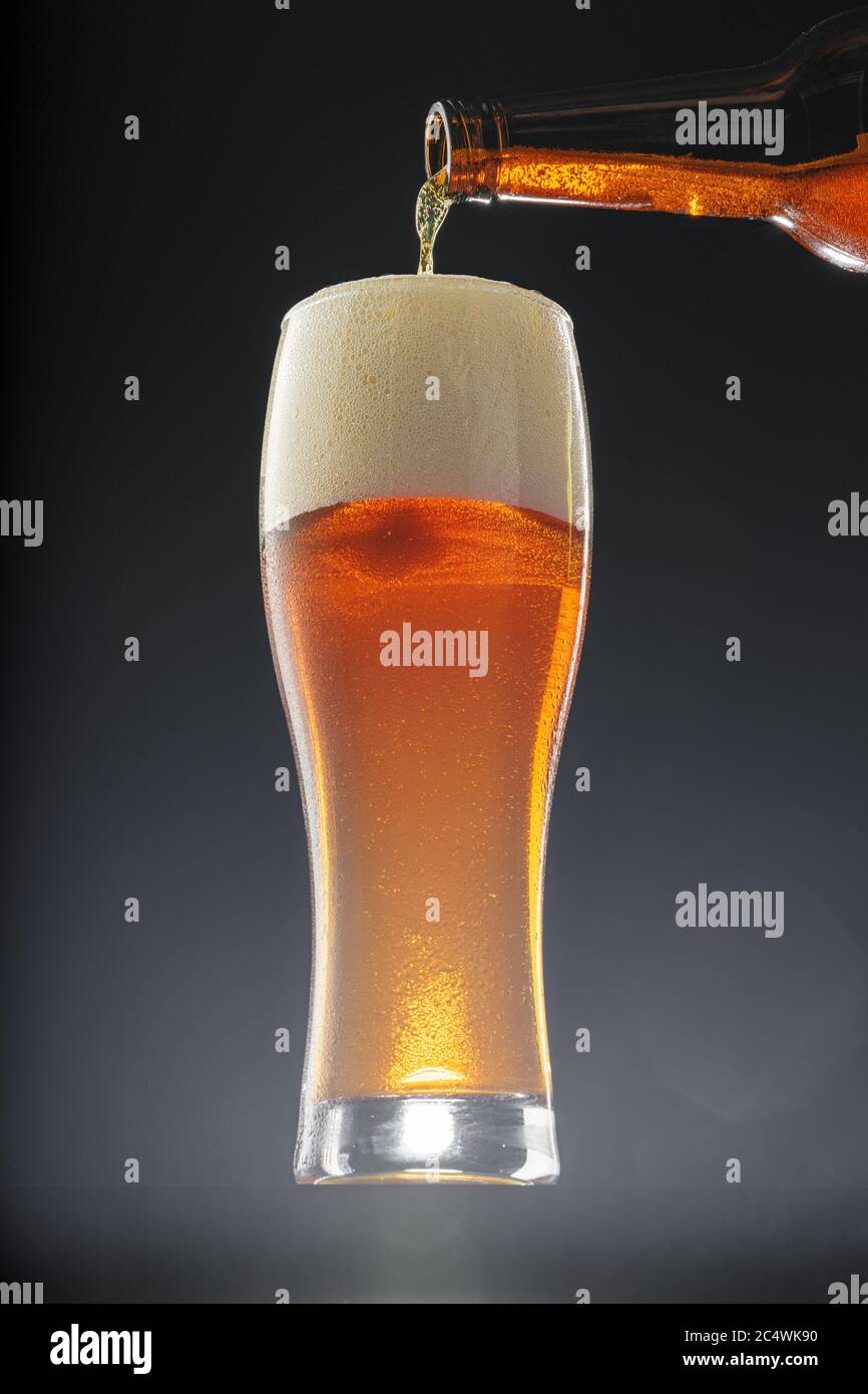 Beer pouring into glass on black background Stock Photo - Alamy