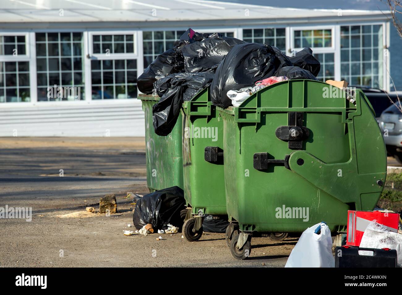 garbage bins are overfilled with packages with waste on the road ...