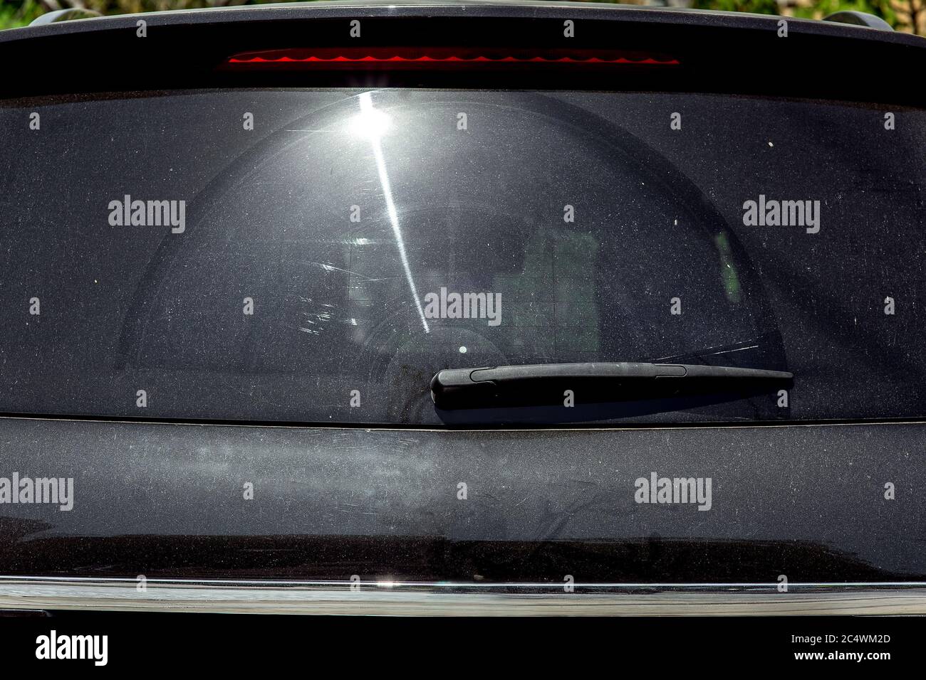 Rear window of a black dirty car covered in dust with a sun flare Stock ...