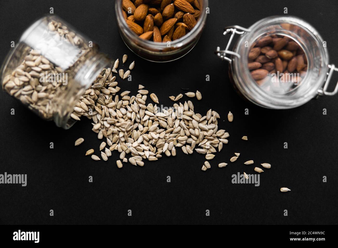 Sunflower seeds scattered on the black table from a jar. Sunflower seed ...