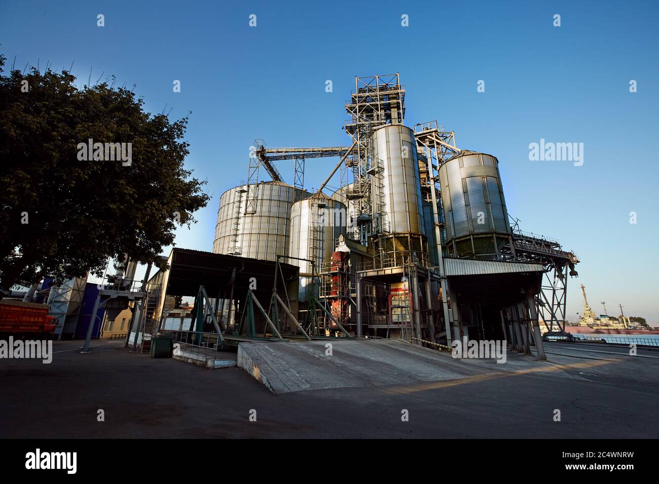 Modern grain terminal on sunset. Metal tanks of elevator. Grain-drying ...