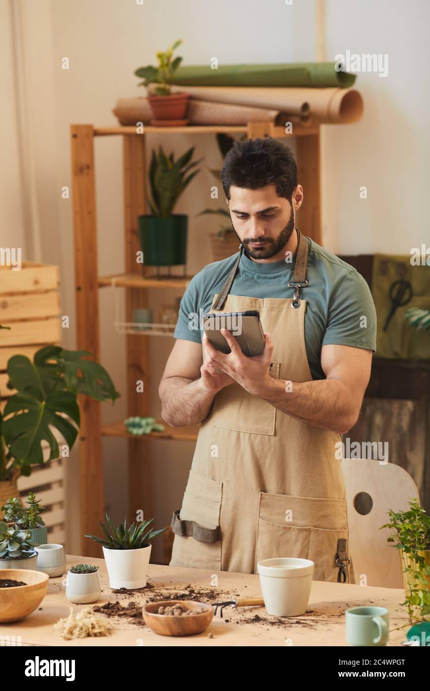 Vertical portrait of handsome bearded man wearing apron and using ...