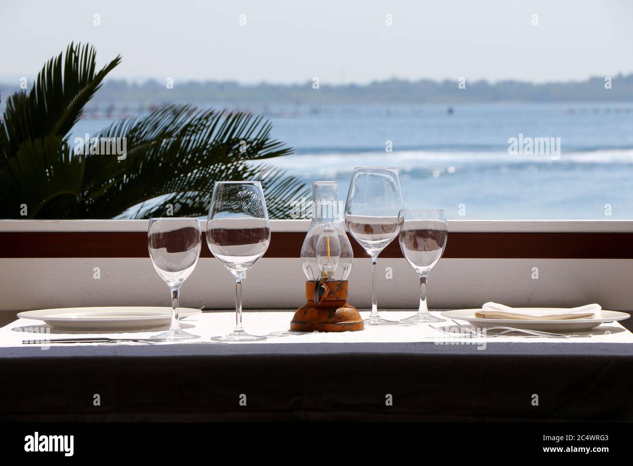 Table set in a restaurant in front of a window overlooking the sea ...