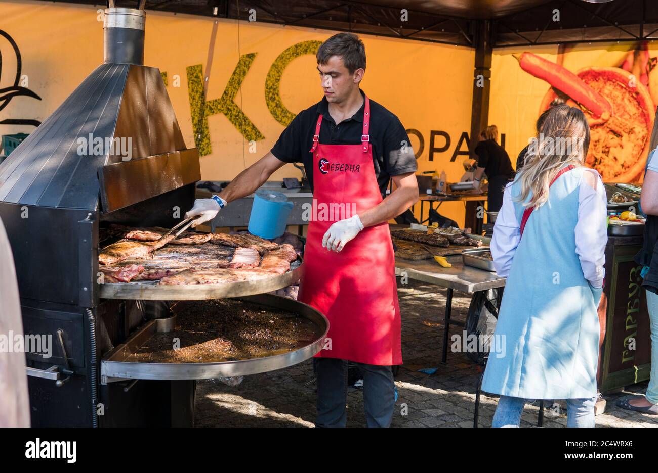 UKRAINE, LUTSK - June 5, 2019: Man is cooking a meat on a grill on a ...
