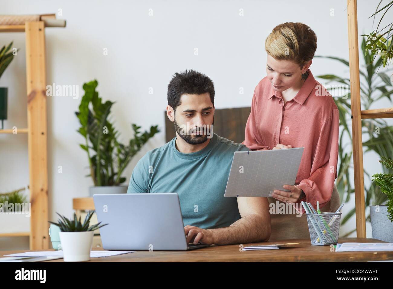 Portrait of female assistant showing documents to handsome bearded man ...