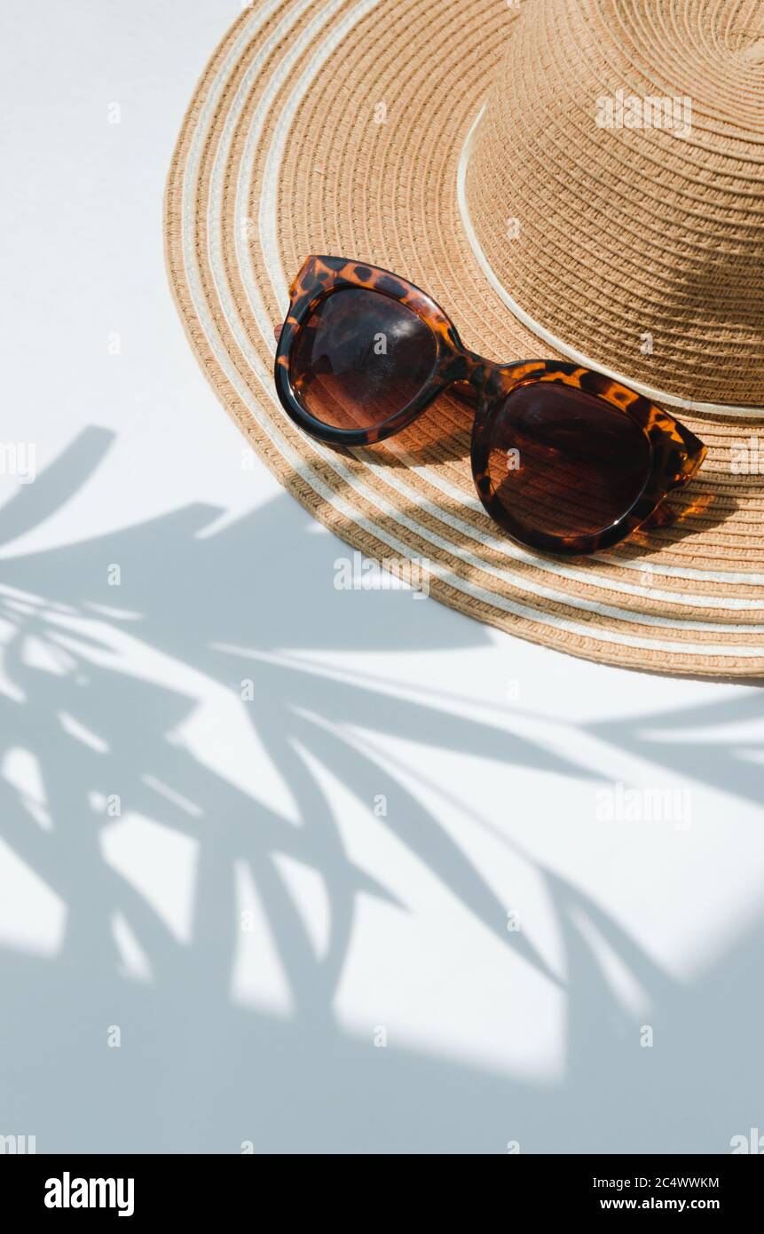 Straw hat and sunglasses in the morning with palm tree shadow and ...