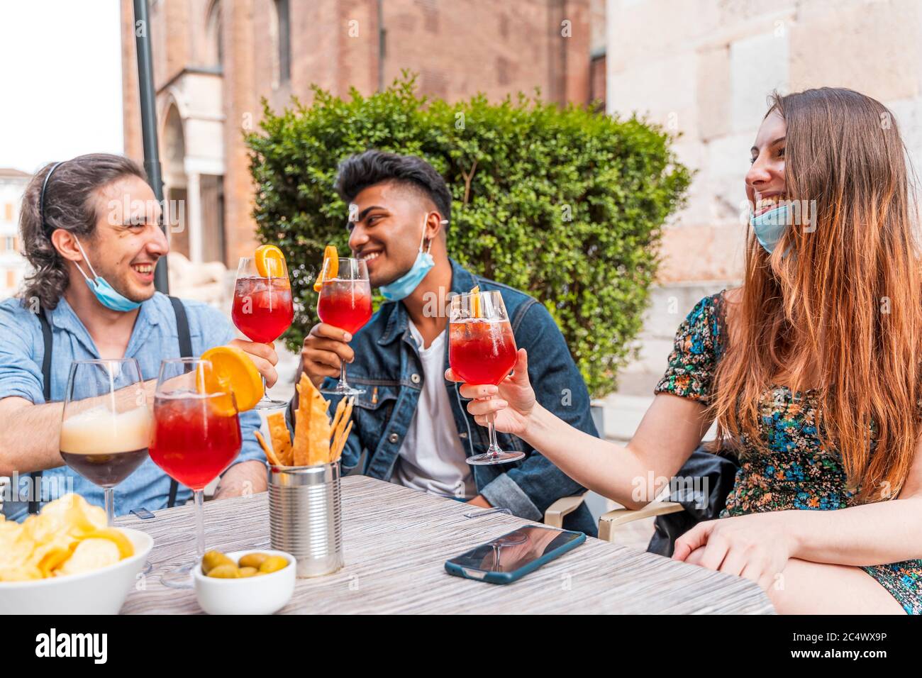 Friends drinking colored cocktail at outdoor bar with face masks - New ...