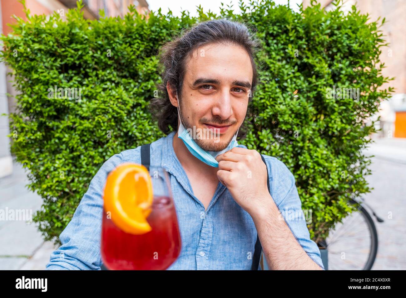 male portrait of young adult drinking colored cocktail at outdoor bar ...