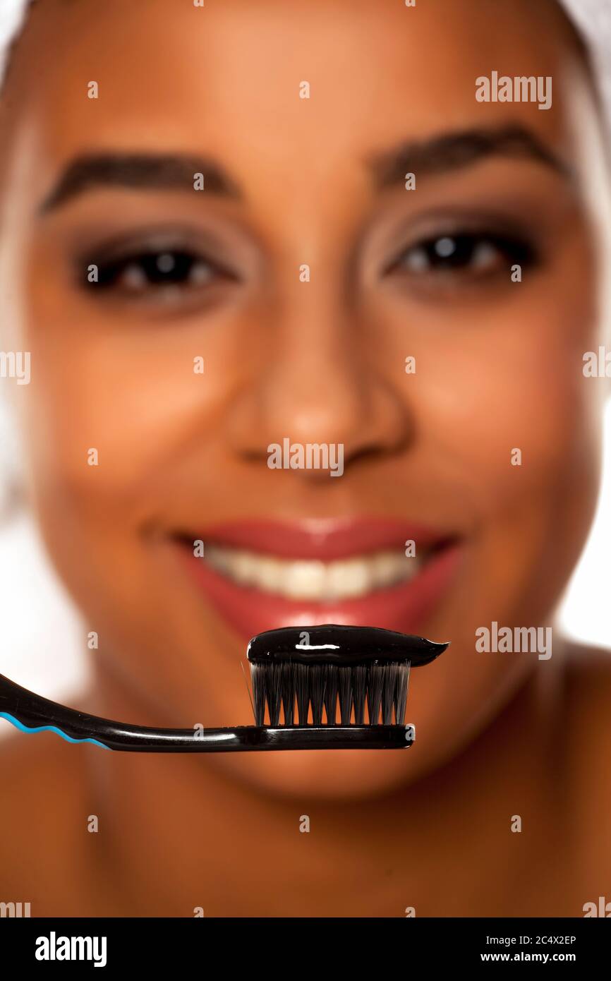 portrait of a happy young dark-skinned woman posing with toothbrush and ...
