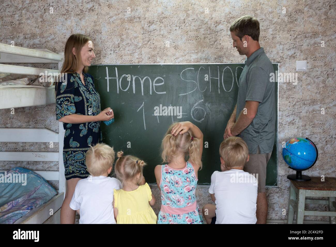 Parents teach their children at the blackboard in their home. Home ...
