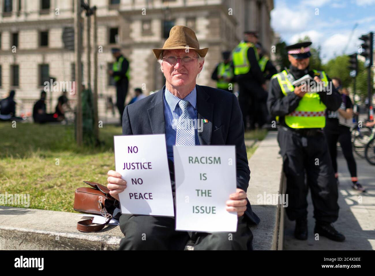 An elderly man sitting with protest signs during a Black Lives Matter ...