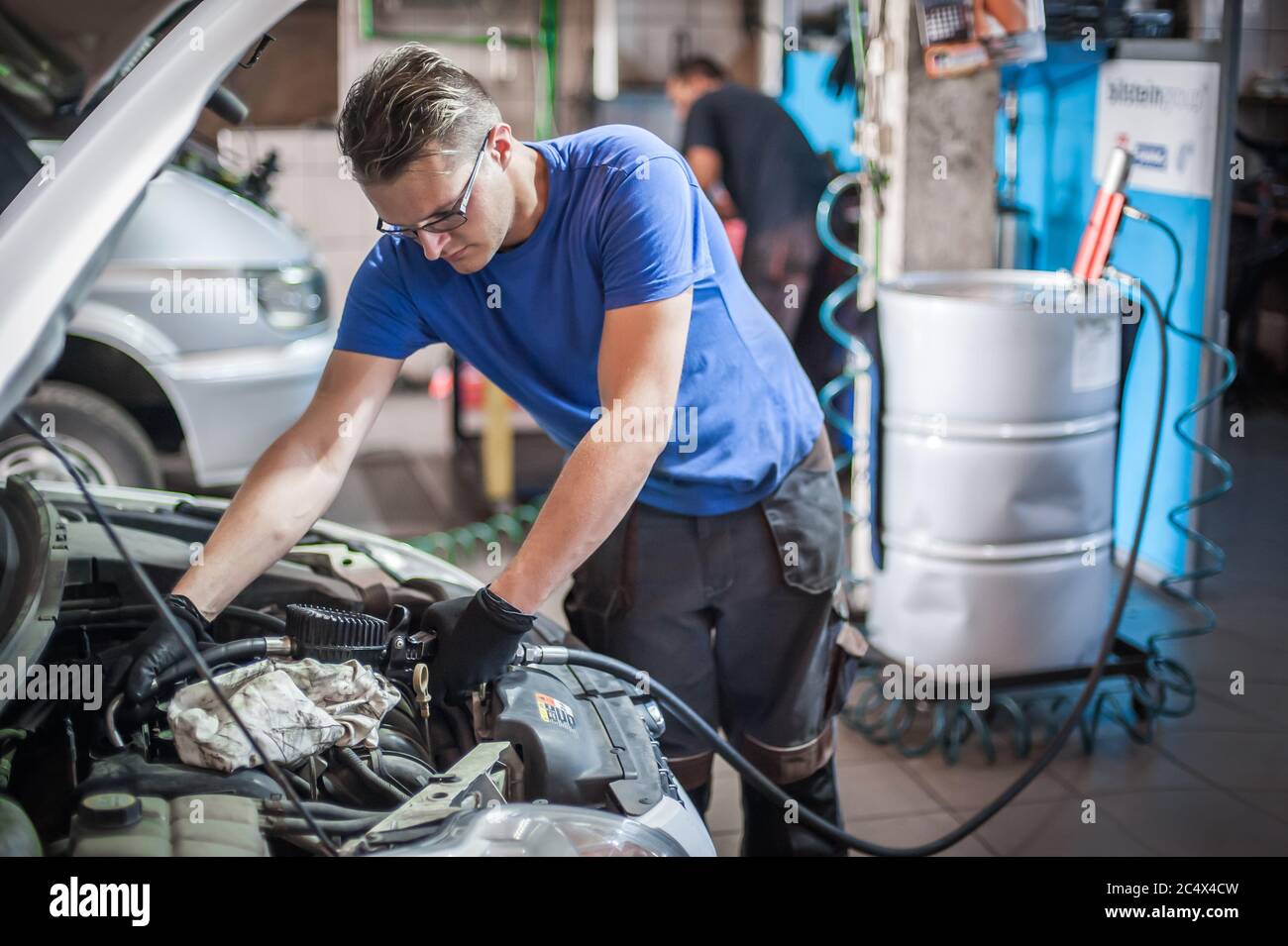 Auto mechanic repairer change old motor oil and pours new oil into the ...