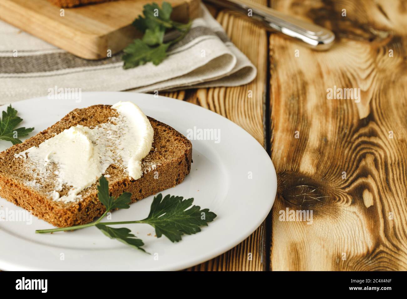Buttered slice of rye bread on wooden table Stock Photo - Alamy