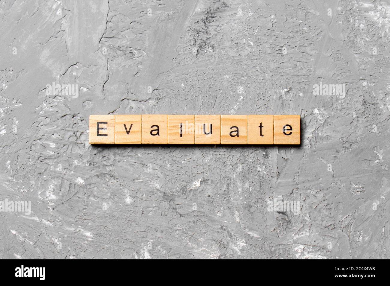 EVALUATE word written on wood block. EVALUATE text on cement table for ...
