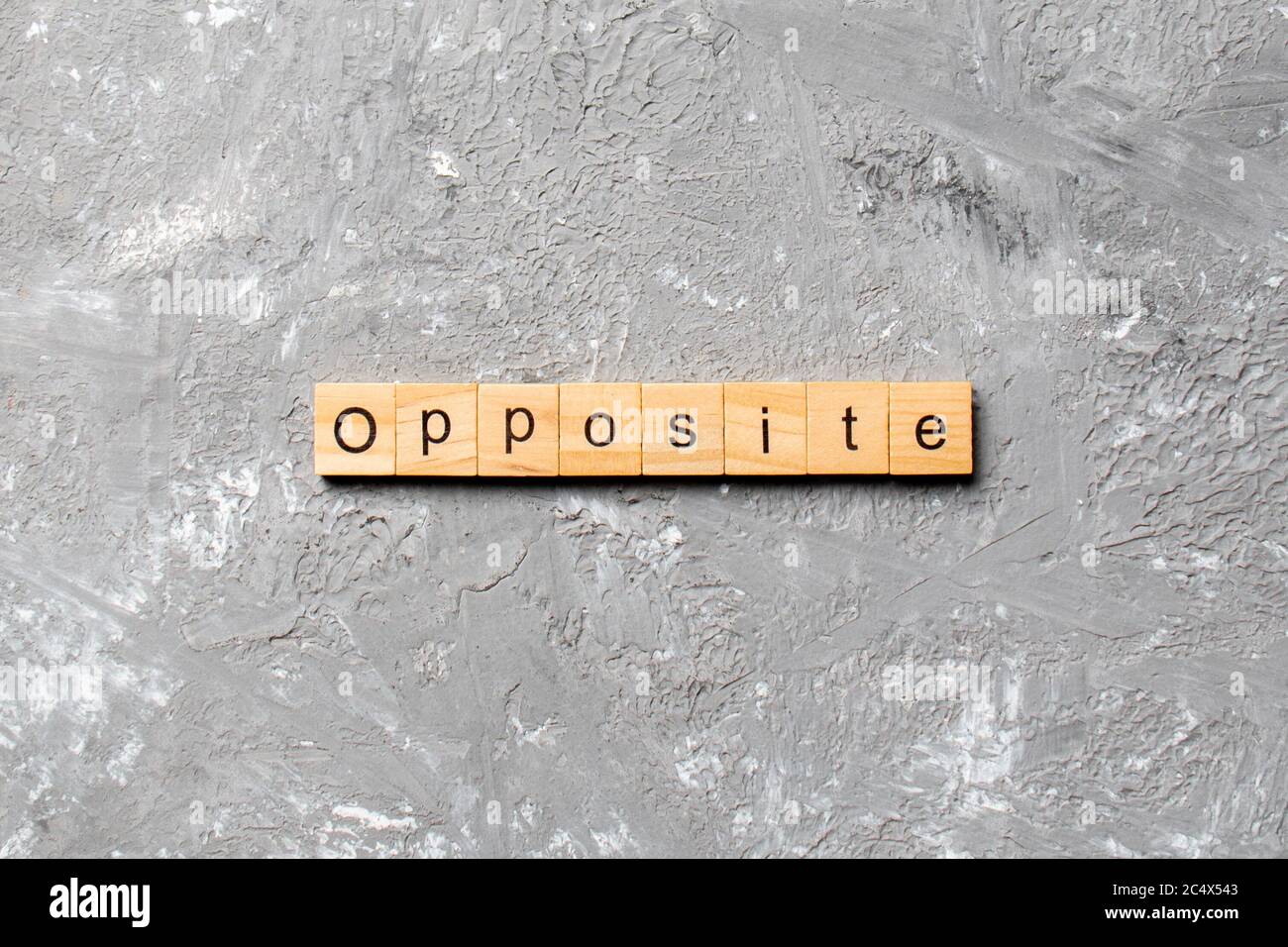 Opposite word written on wood block. Opposite text on cement table for ...