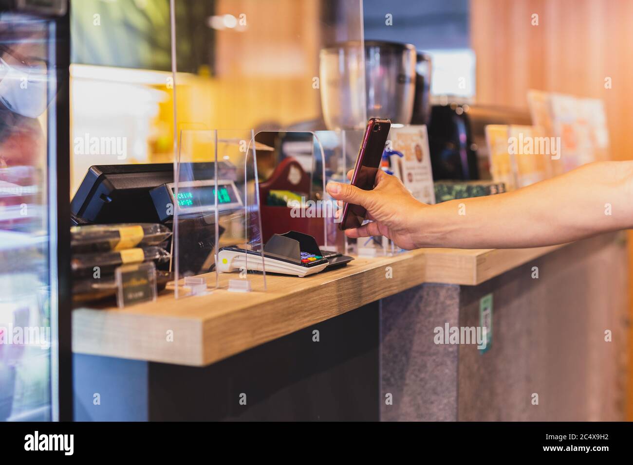 New nomarl customer paying bill by cell phone with staff behid plastic ...