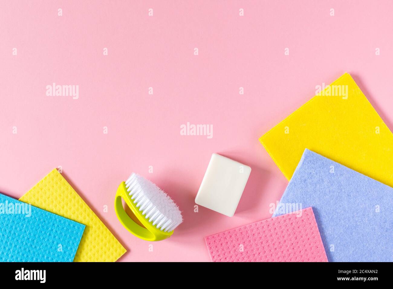 Multi-colored cloths and soap with brush on pink background ...