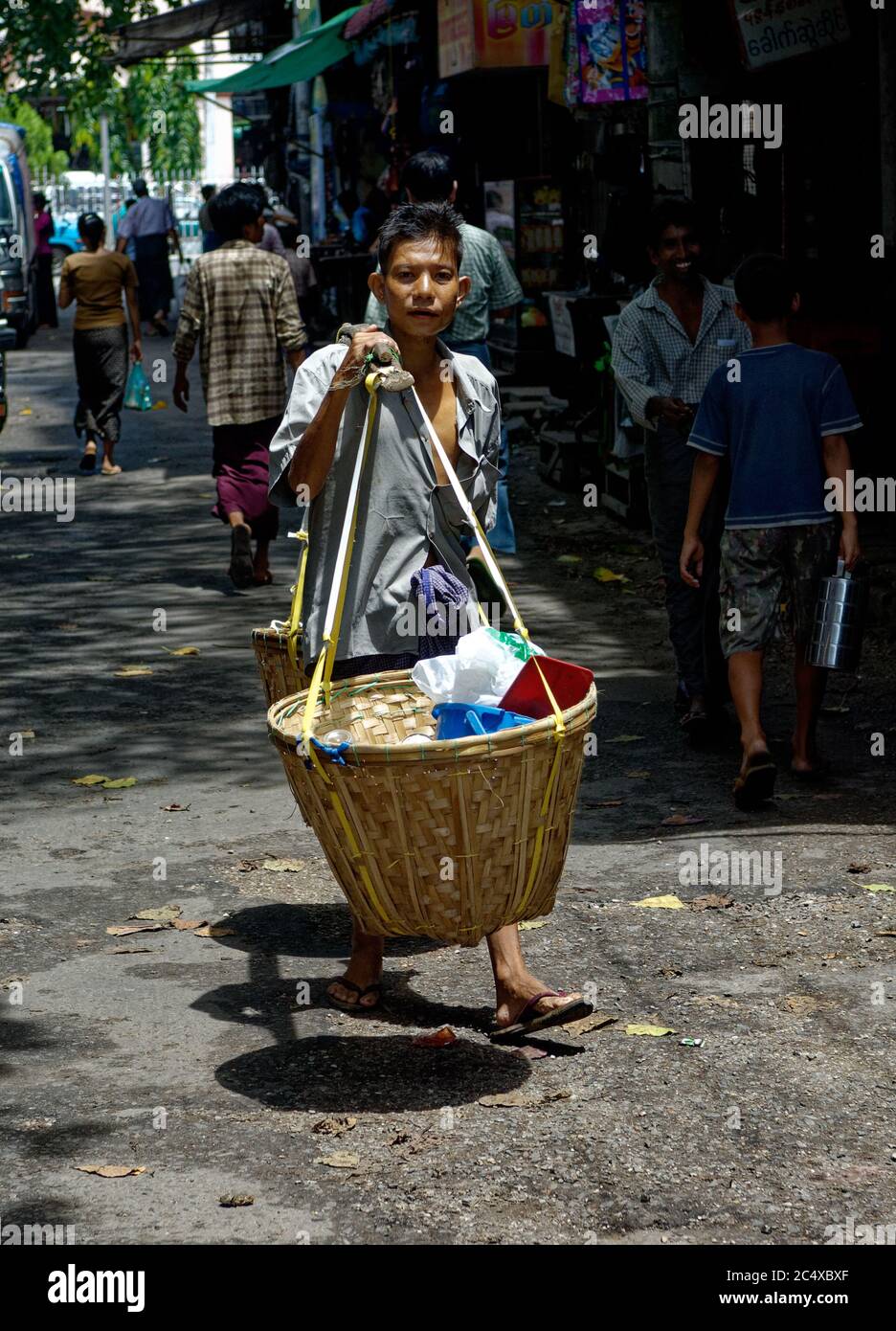 Man carrying goods in wicker baskets on a wooden pole through the ...