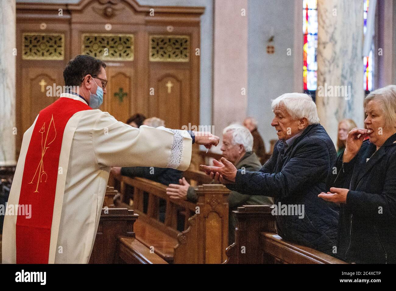 A priest handing out holy communion to parishioners at the Cathedral of ...