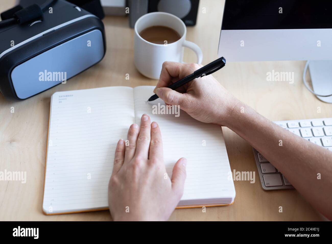 Caucasian woman sitting by her desk and writing in her notebook Stock ...