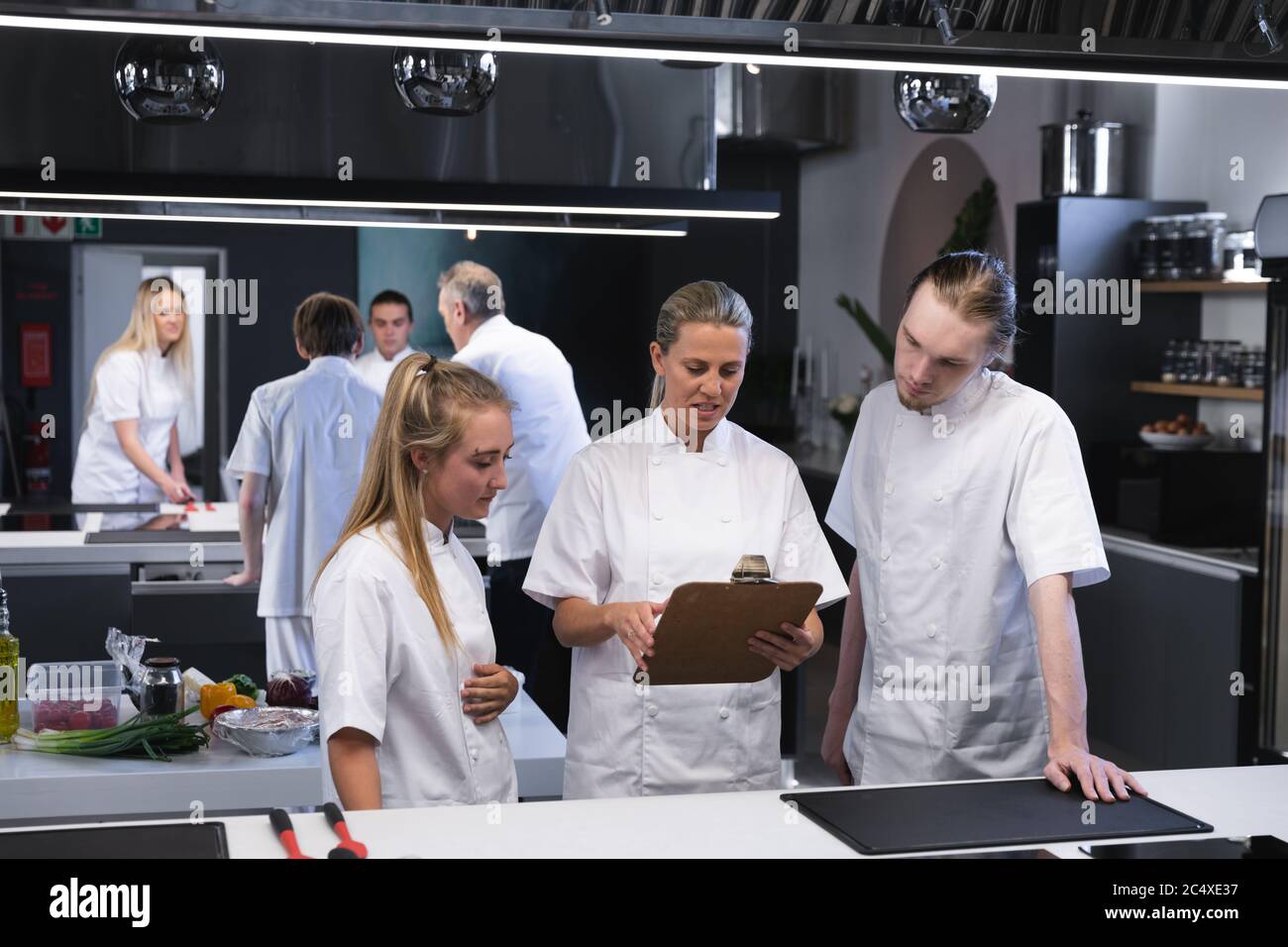 Group of chefs looking at the clipboard while standing at restaurant ...