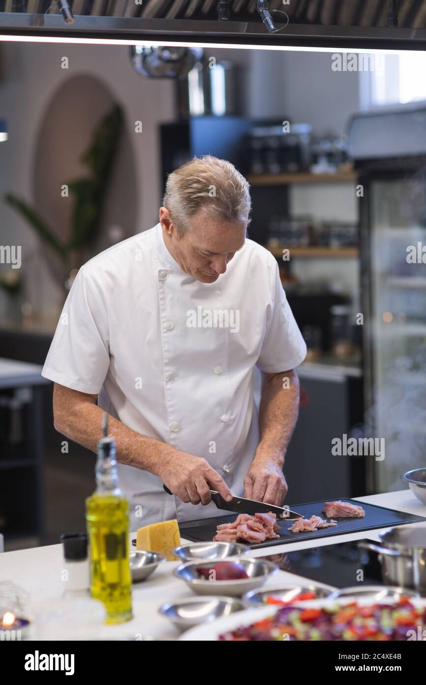 Senior male chef cutting meat at restaurant kitchen Stock Photo - Alamy