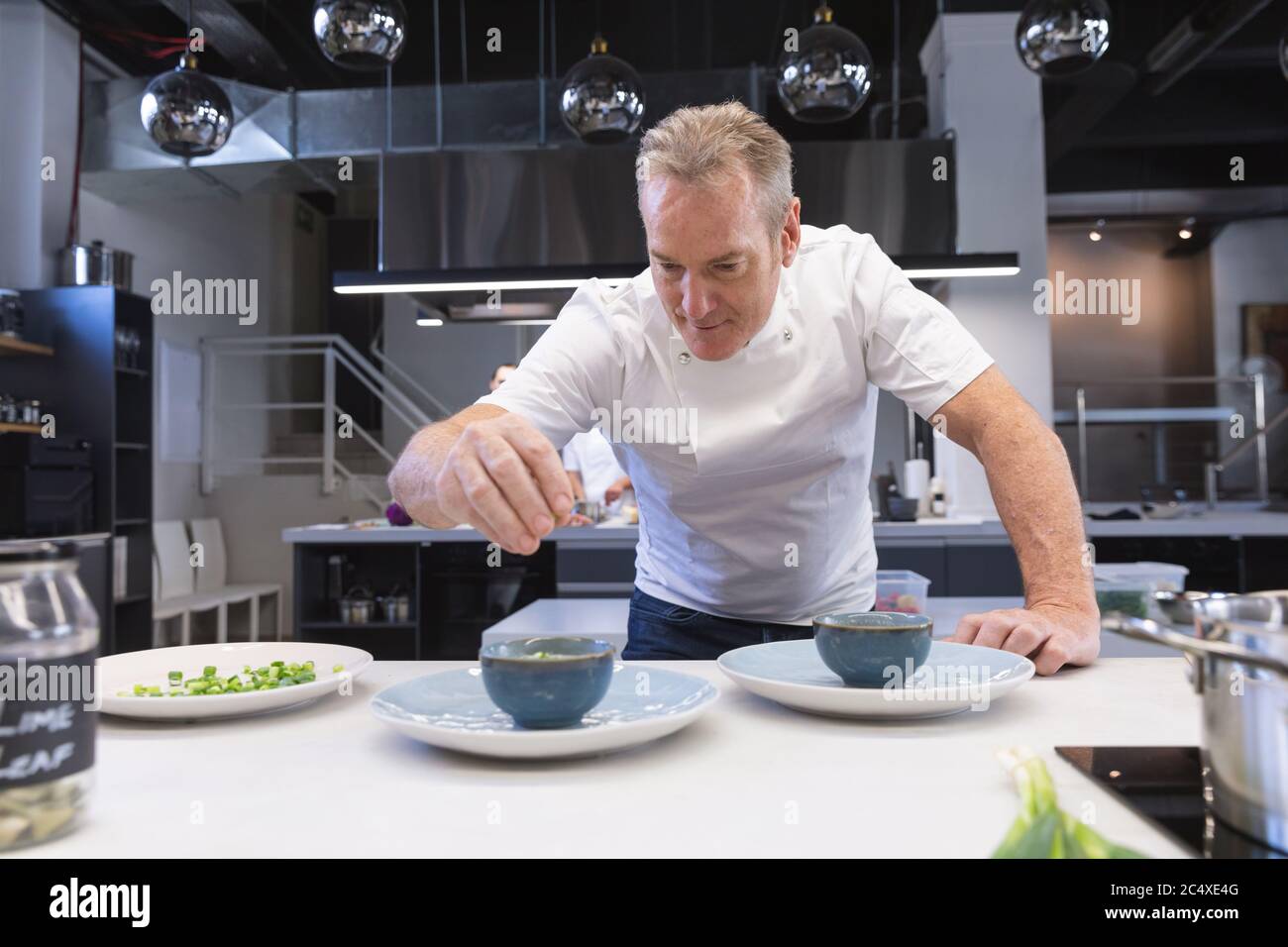 Senior male chef adding salt in a dish at restaurant kitchen Stock ...