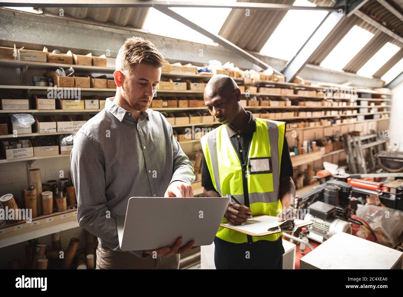 Two male factory workers discussing over a laptop at the factory Stock ...