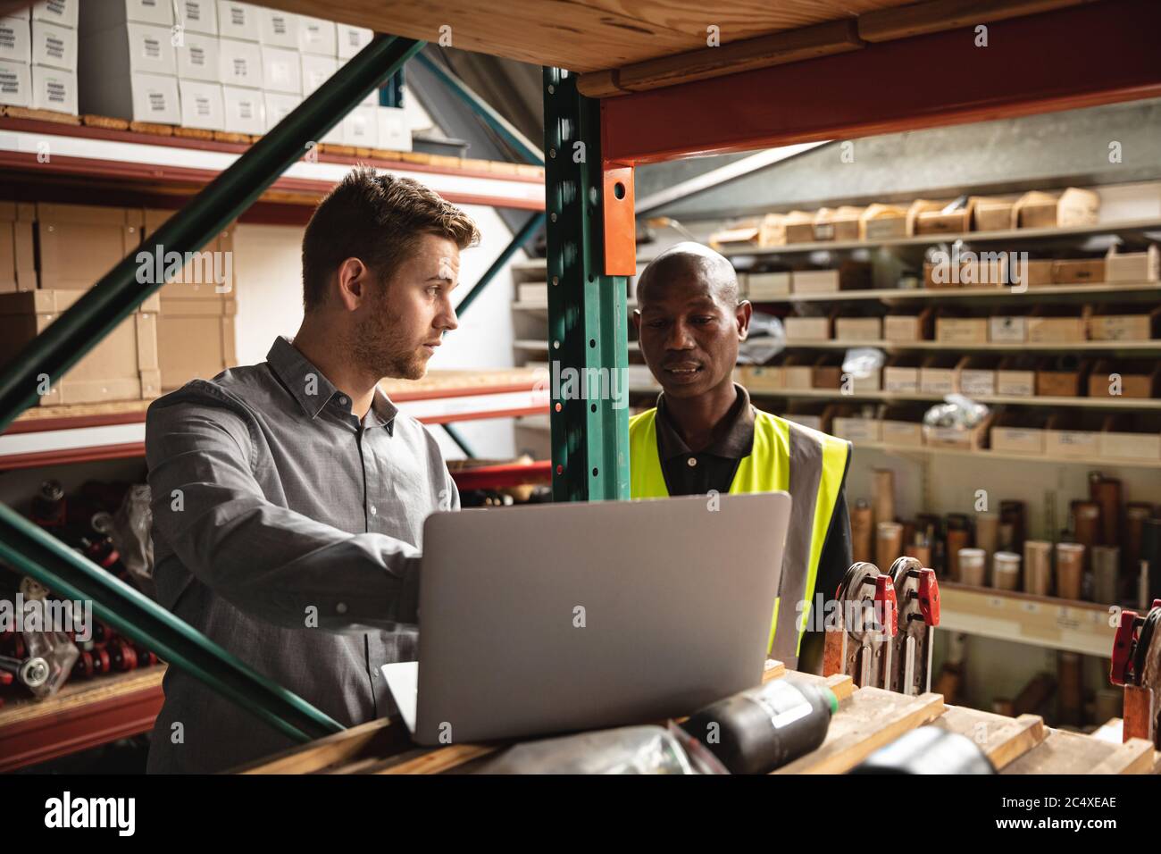 Two male factory workers discussing over a laptop at the factory Stock ...