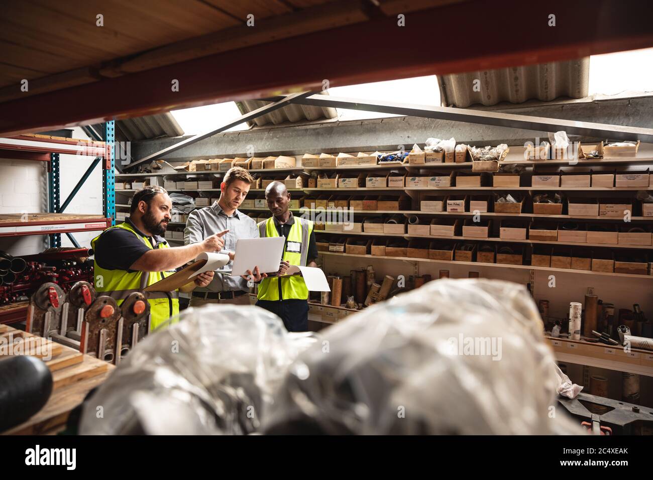 Three male factory workers discussing over a laptop at the factory ...