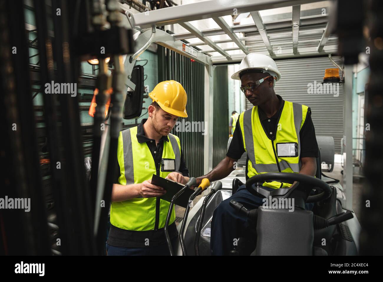 Two male factory workers discussing over a digital tablet at the ...