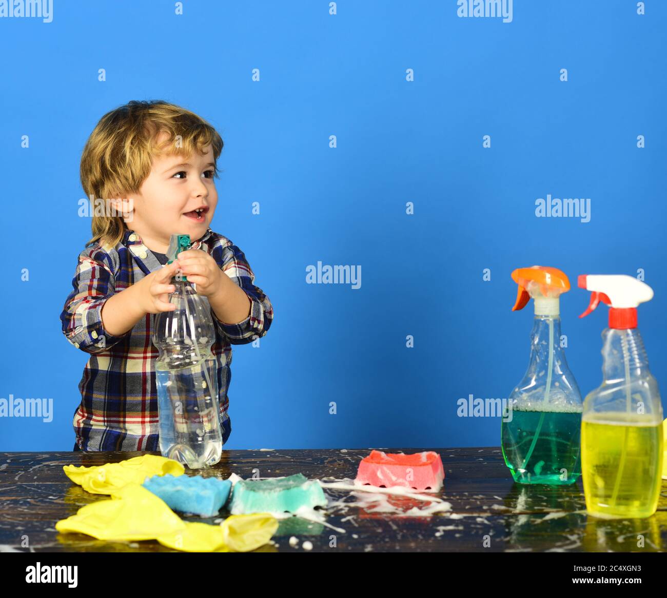 Parents little helper concept. Kid holds spray on table and spraying ...