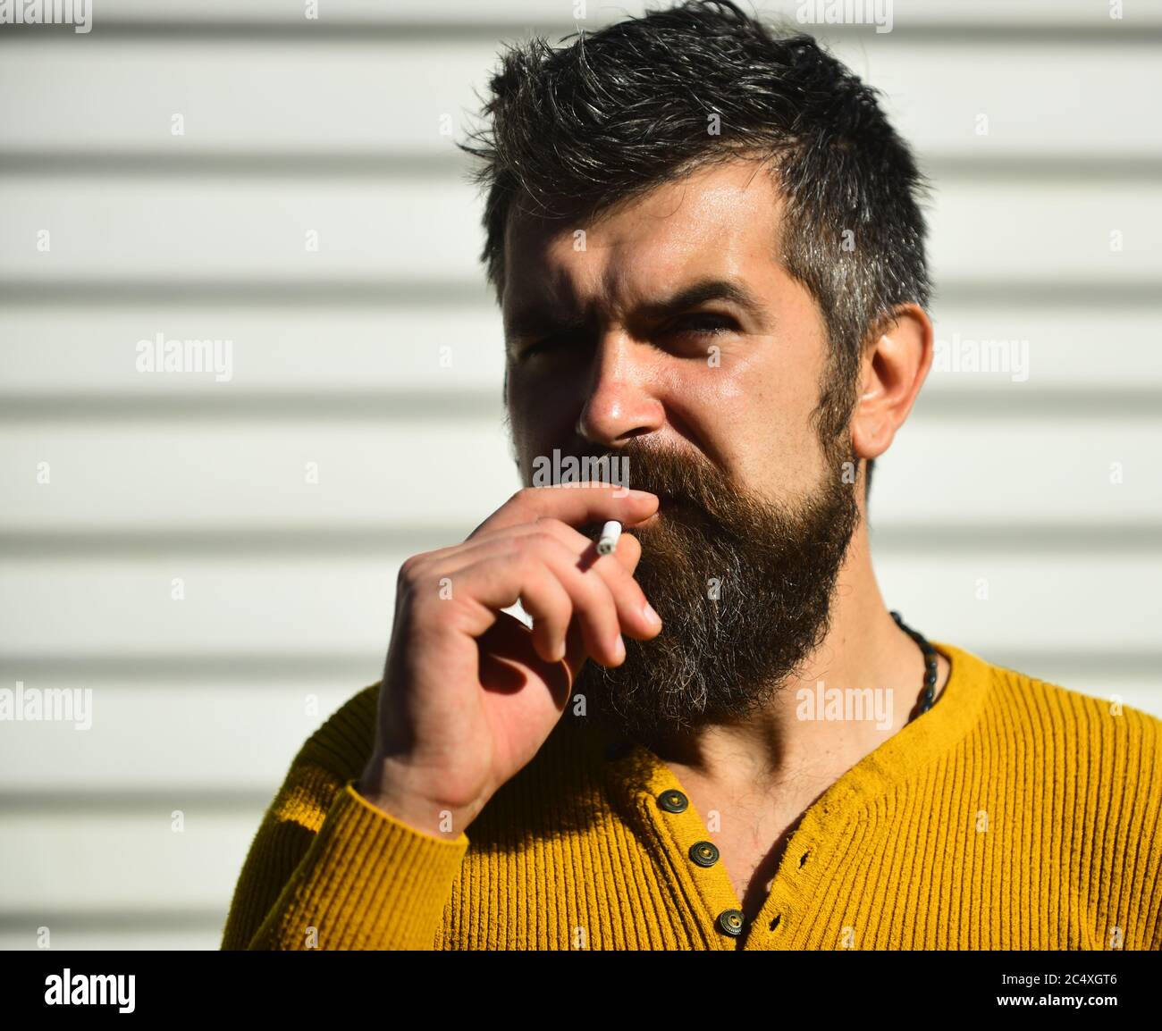 Cool macho man with beard and warm clothes smoking cigarette on the ...