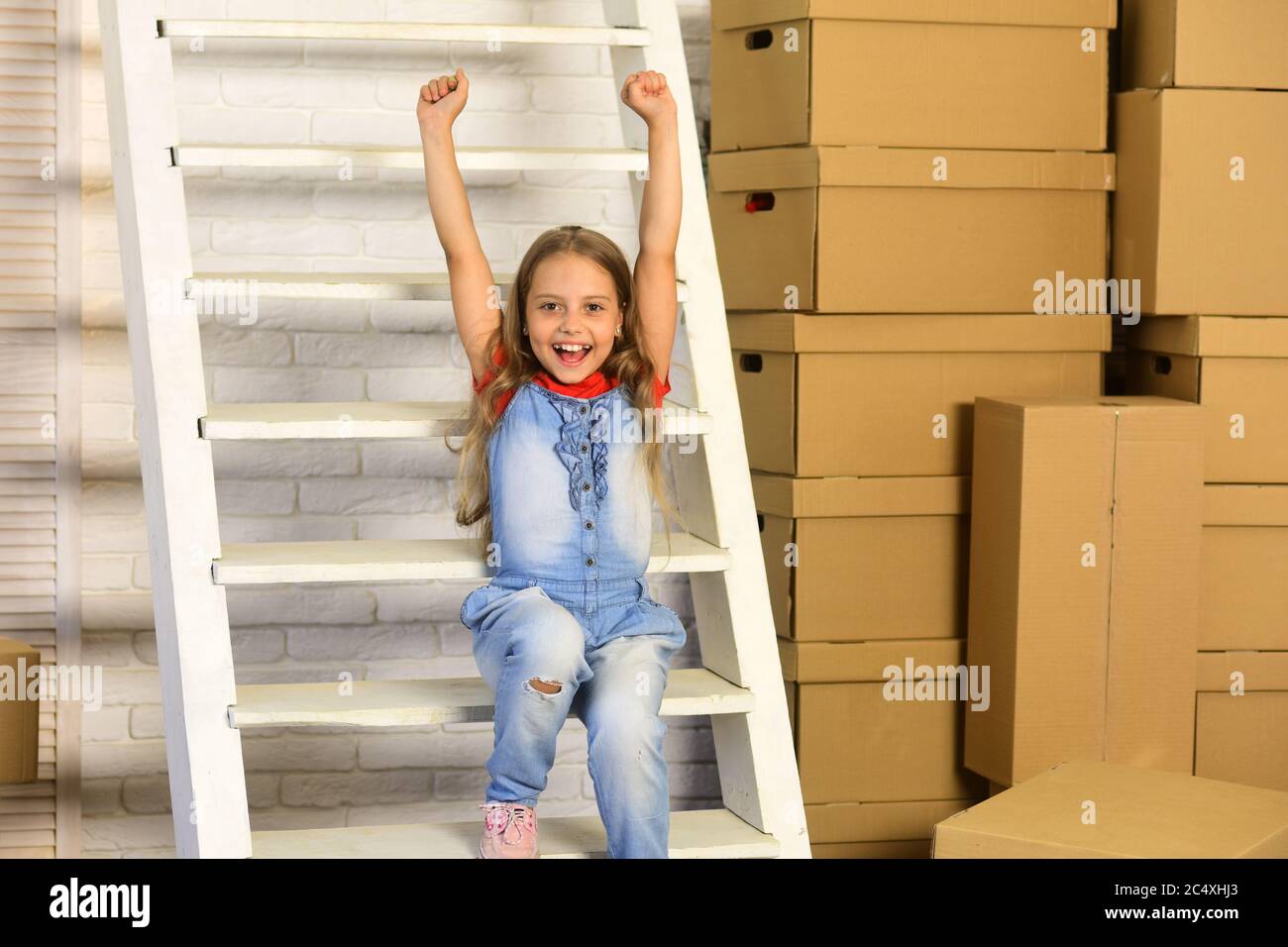 Girl with cheerful face with stairs and pile of boxes on background ...