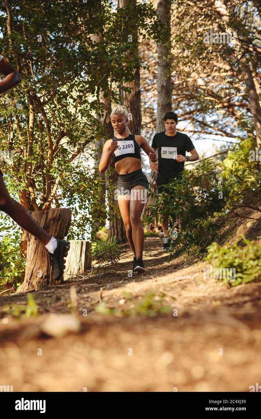 Woman runner running on mountain trail with at male athlete behind her ...