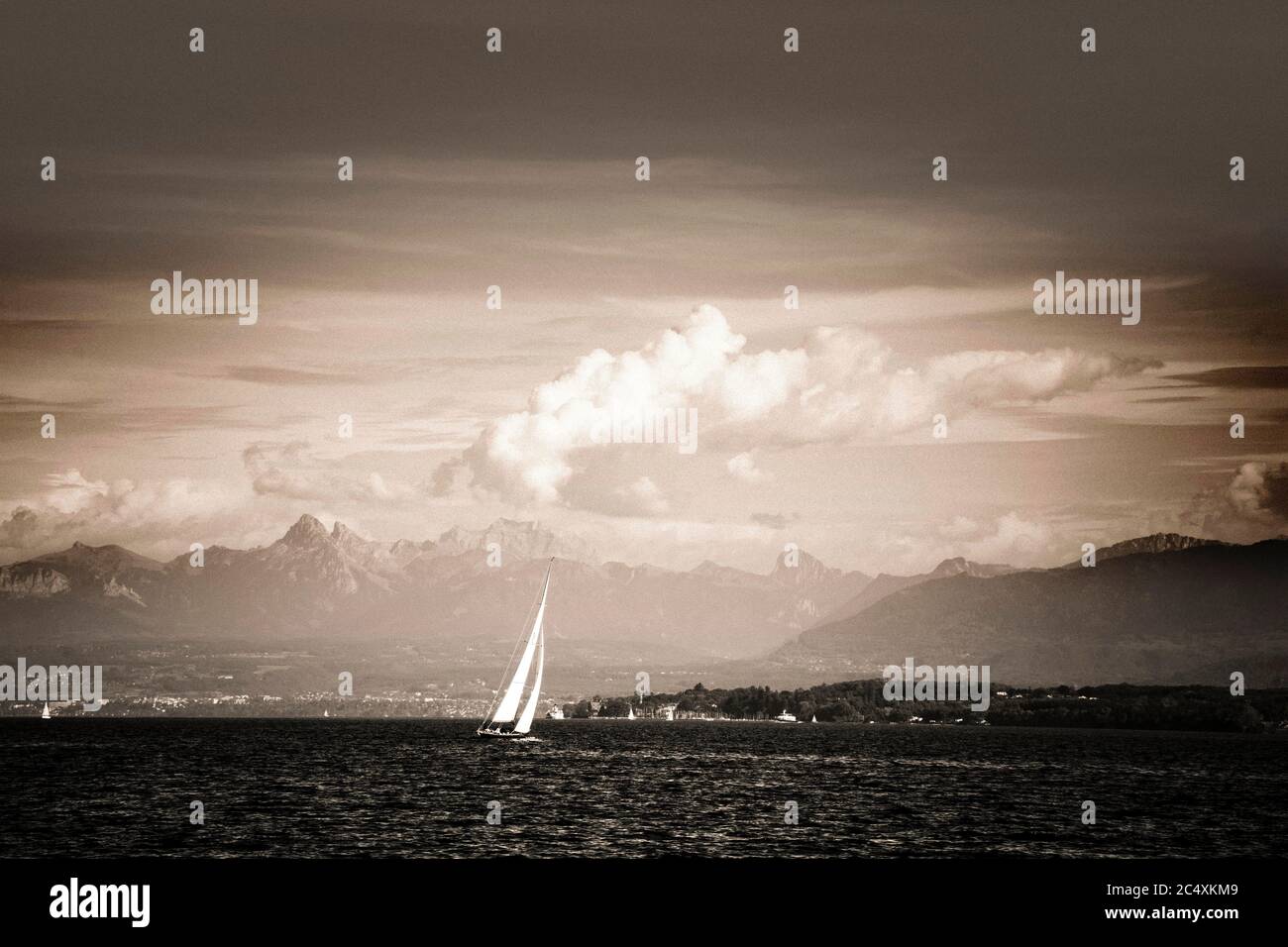 Sailboat gliding across Lake Geneva with the French Alps in the ...